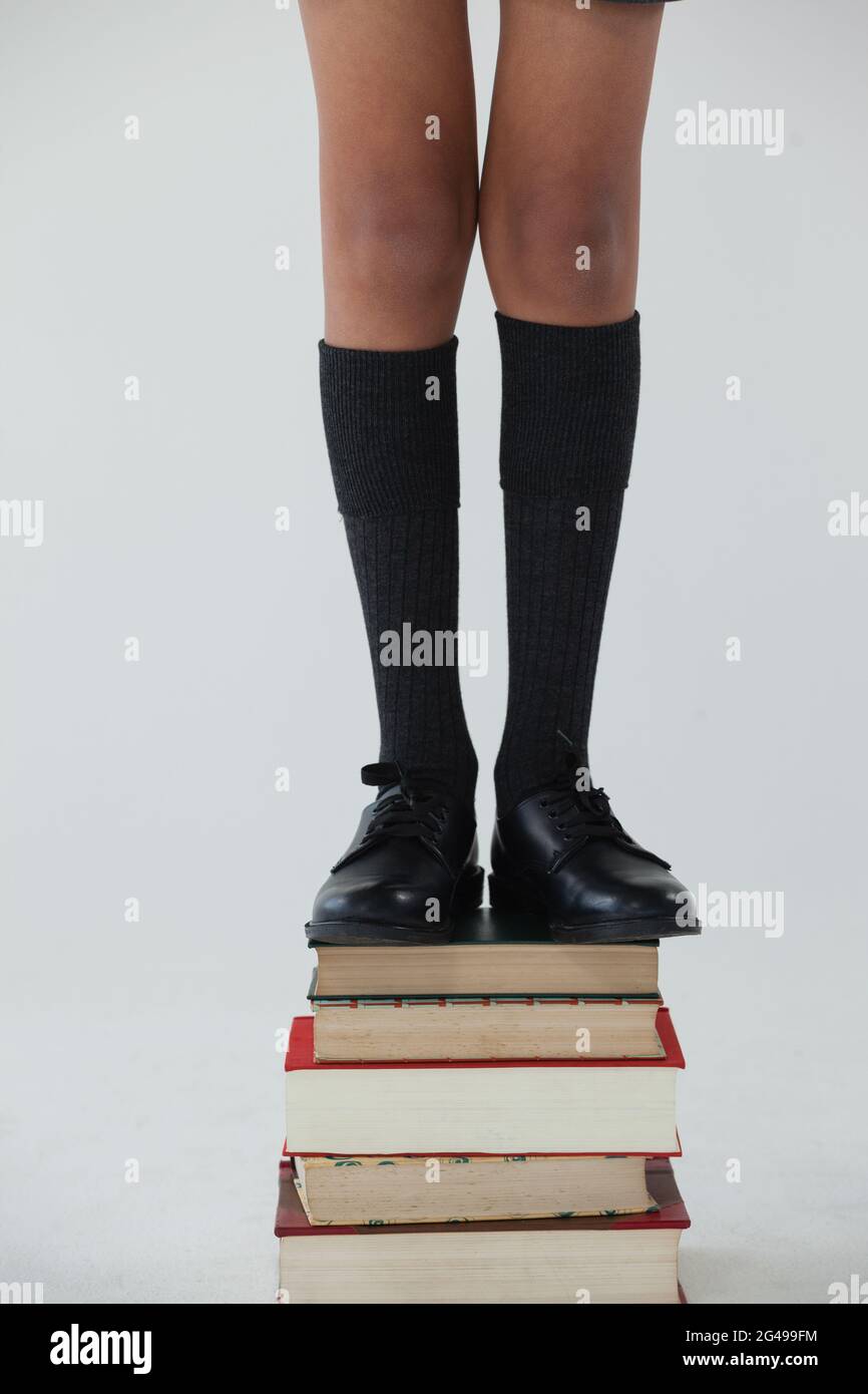 Low-section of schoolboy standing on books stack Stock Photo - Alamy
