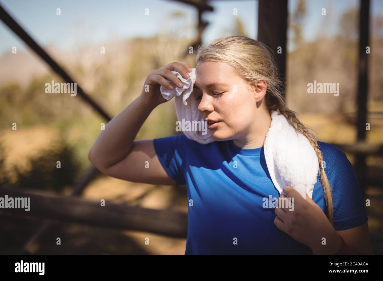 Tired woman wiping sweat after workout during obstacle course Stock ...