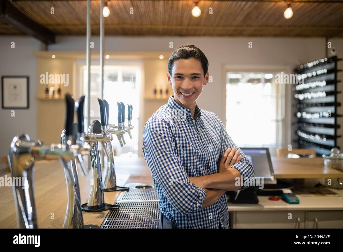 Smiling man with arms crossed at counter in restaurant Stock Photo - Alamy