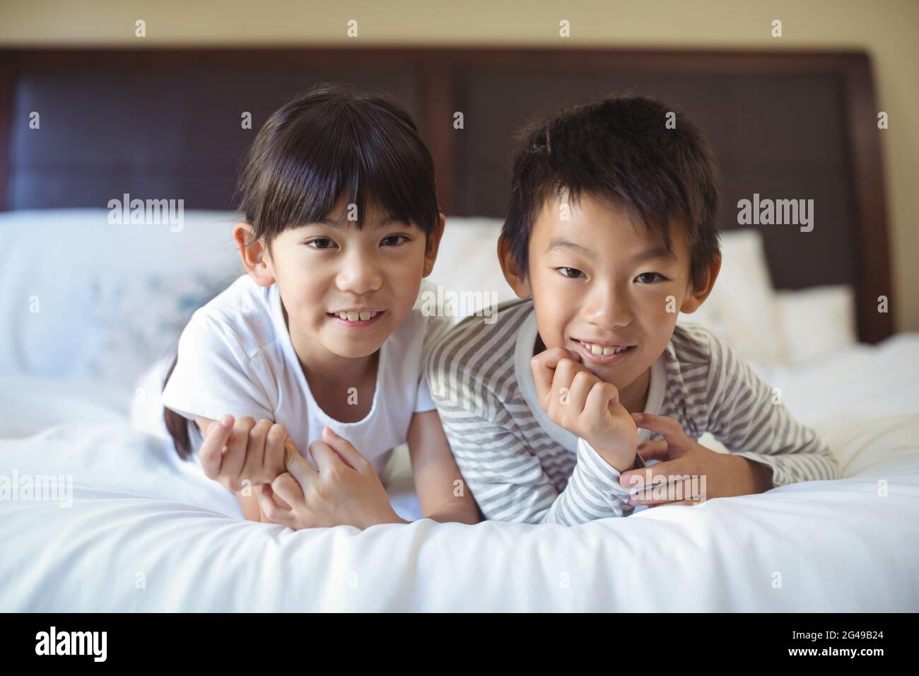 Siblings relaxing on bed in bedroom Stock Photo - Alamy