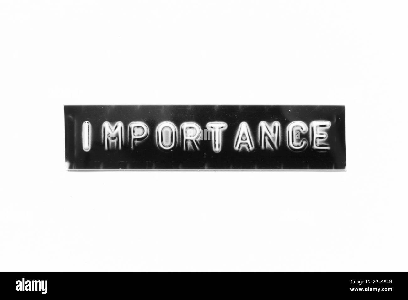 Embossed letter with word importance in black banner on white paper ...