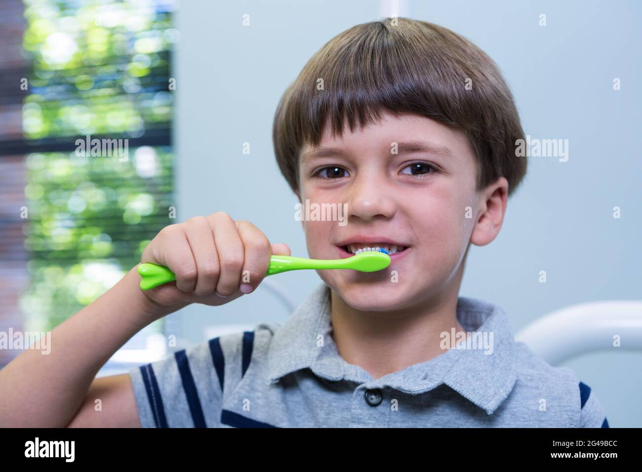 Boy holding toothbrush while sitting on chair at medical clinic Stock ...