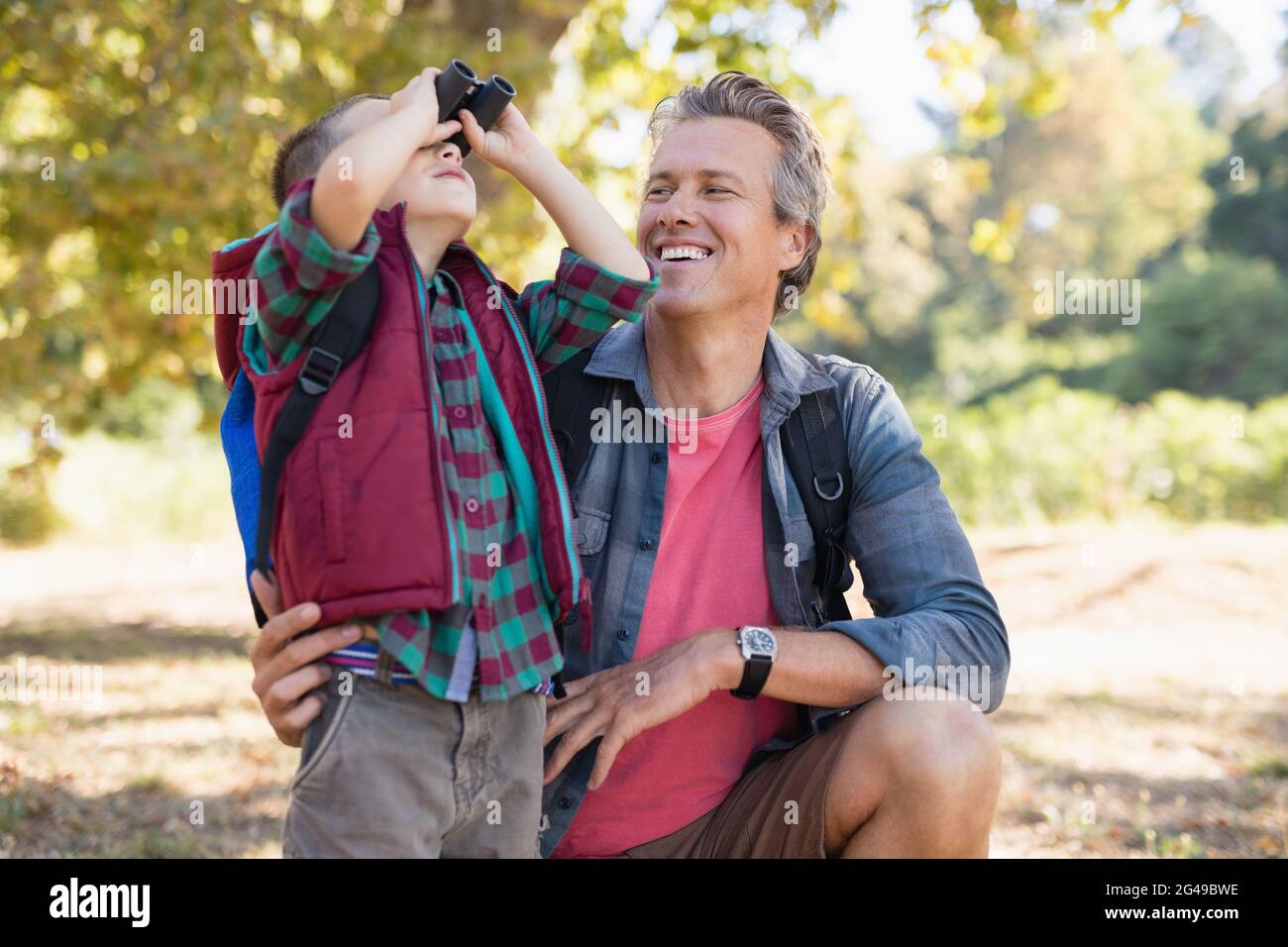 Father watching at boy looking through binoculars Stock Photo - Alamy