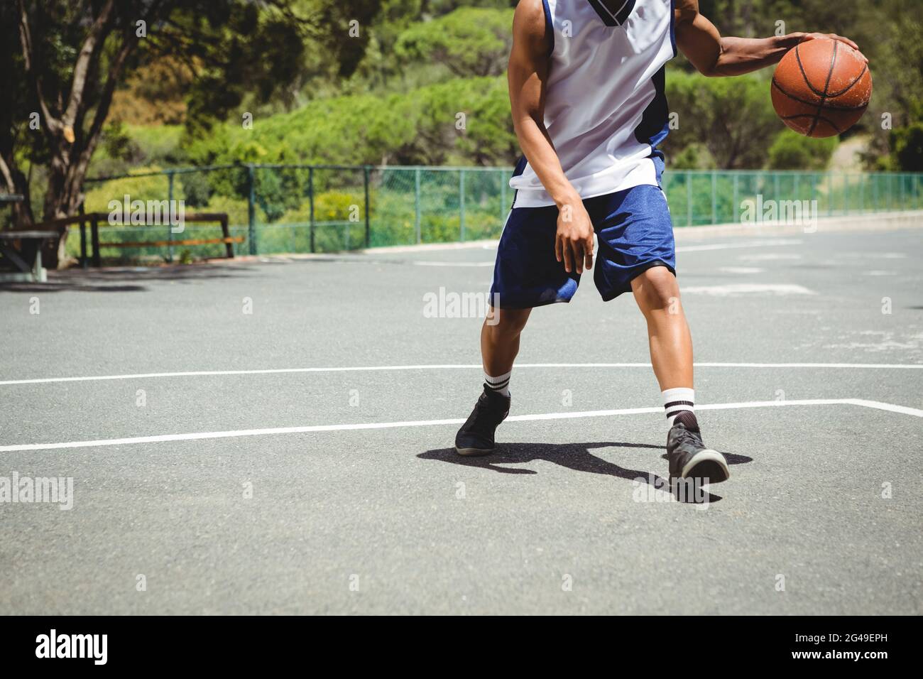 Low section of male teenager practicing basketball Stock Photo - Alamy