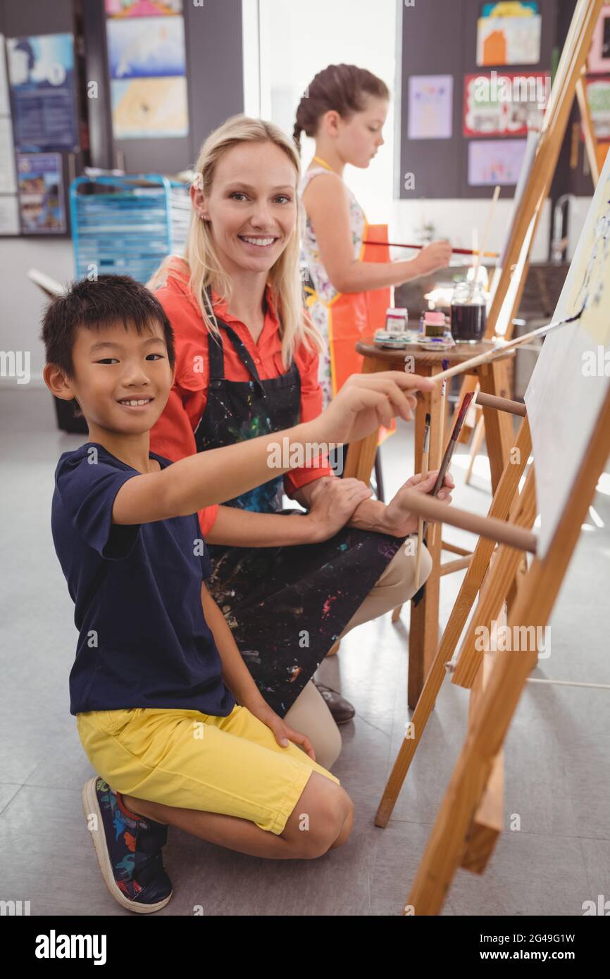Teacher assisting schoolboy in drawing class Stock Photo - Alamy