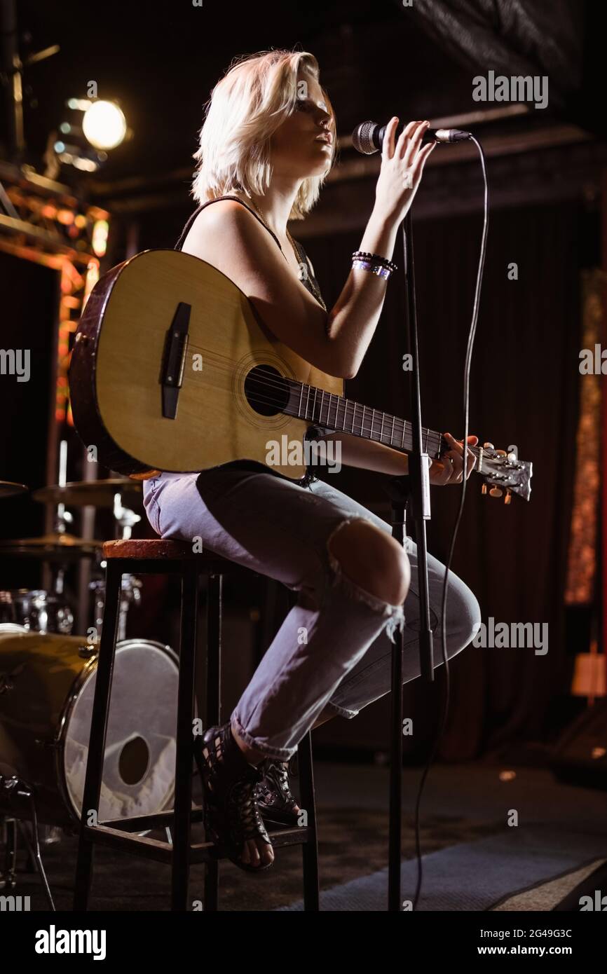 Performer singing while holding guitar at nightclub Stock Photo - Alamy
