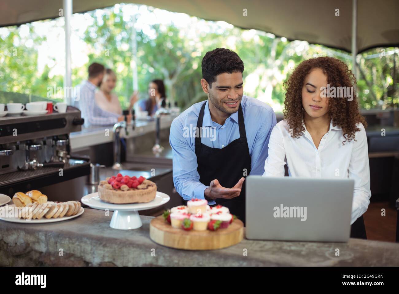 Male waiter and female waitress with laptop Stock Photo - Alamy