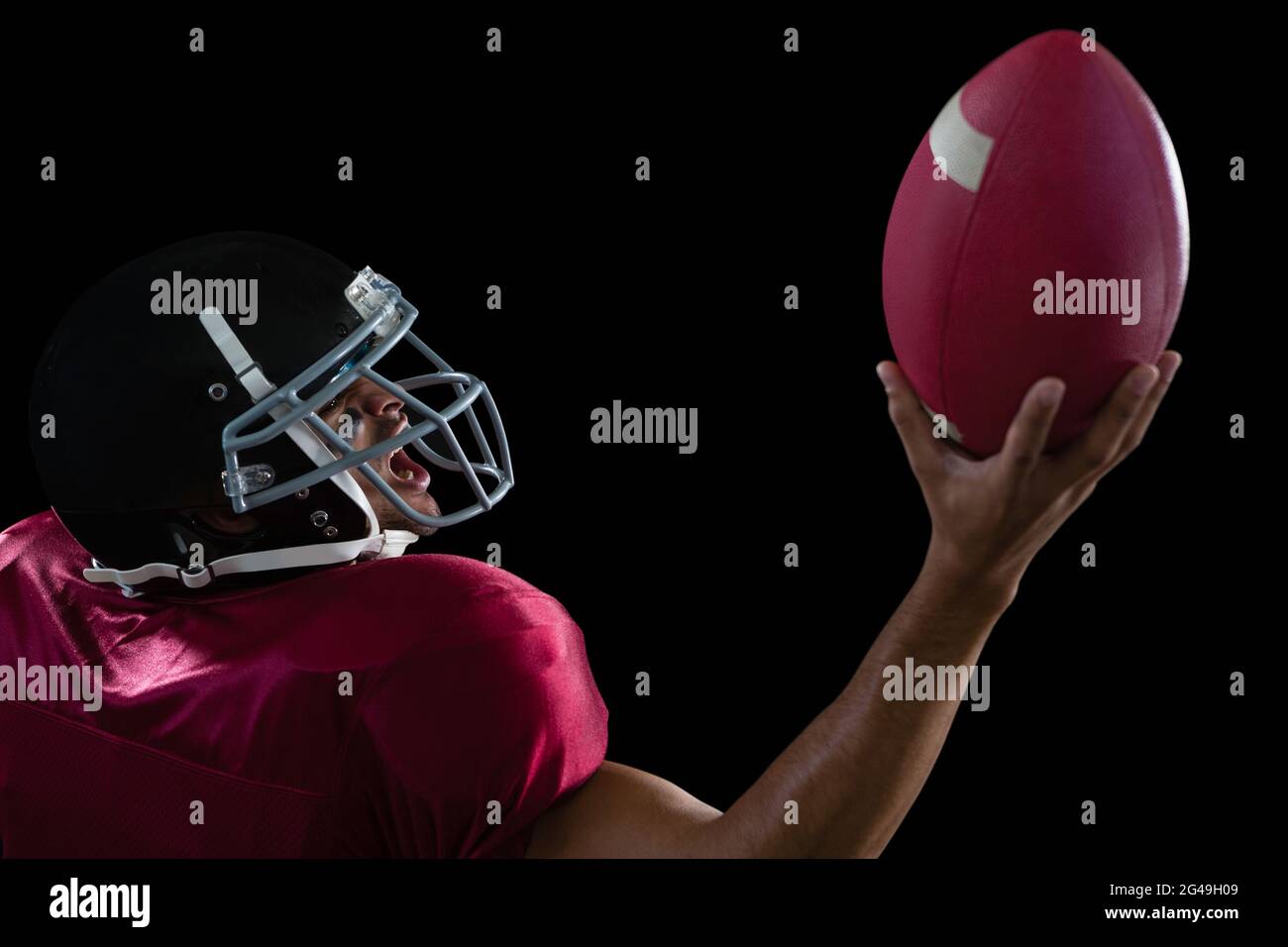 American football player holding a ball in one hand Stock Photo - Alamy