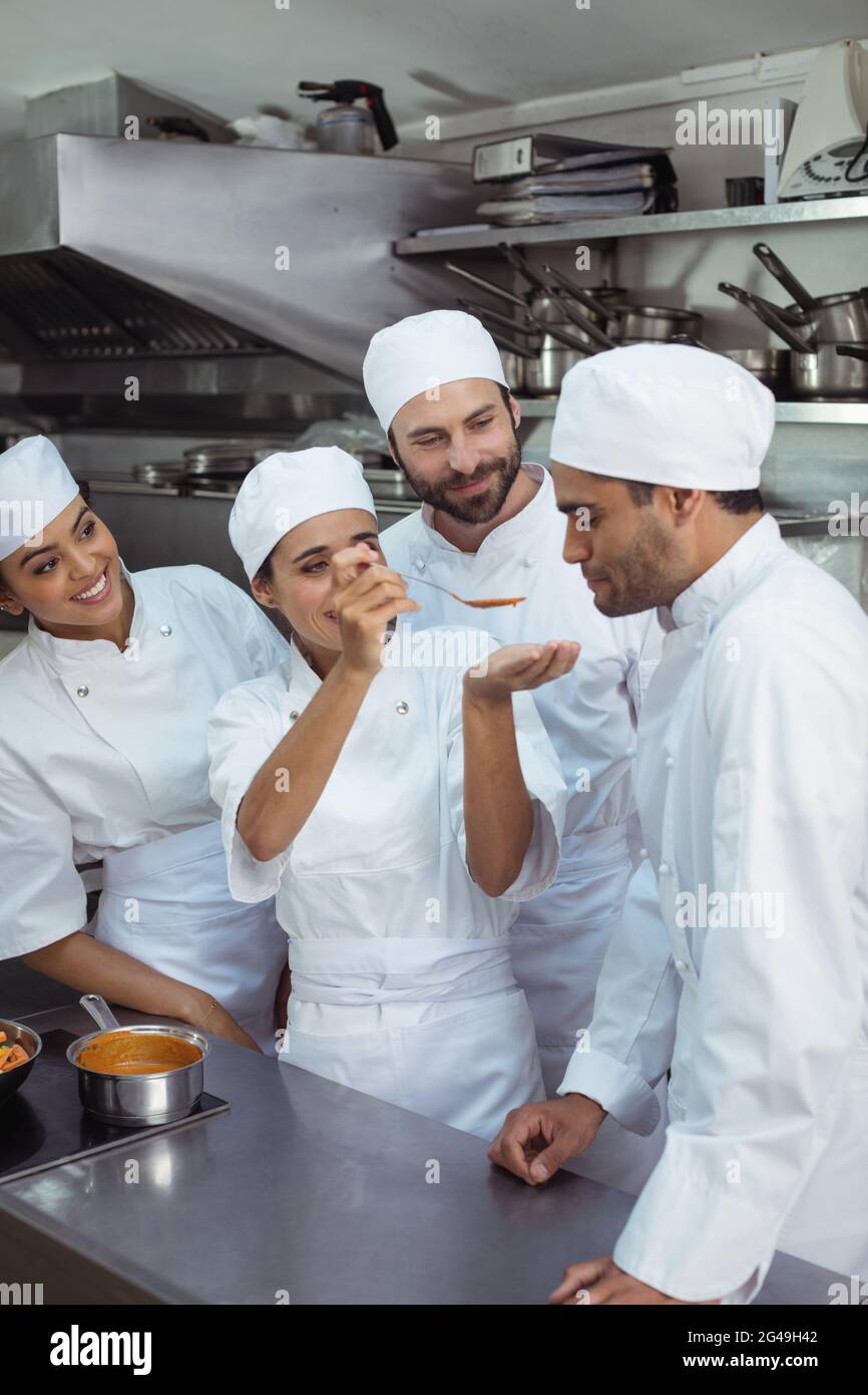 Chef tasting food to colleague in kitchen Stock Photo - Alamy