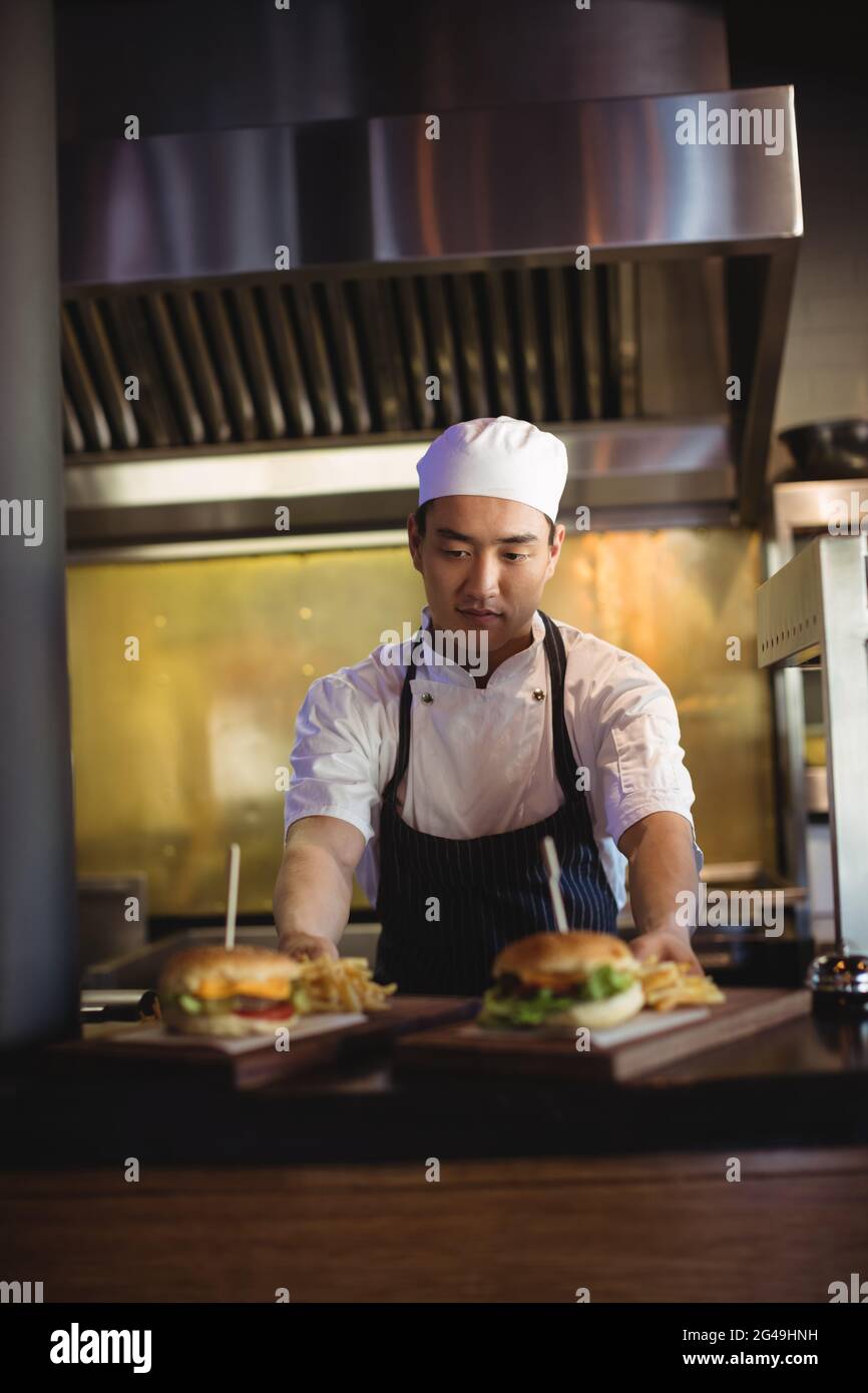 Chef placing tray with french fries and burger at order station Stock ...