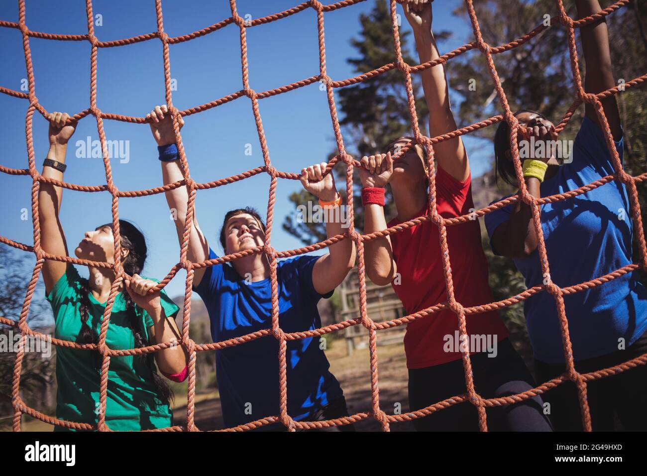 Group of fit woman climbing a net during obstacle course training Stock ...