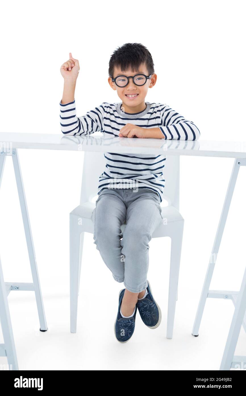 Boy sitting on chair against white background Stock Photo - Alamy