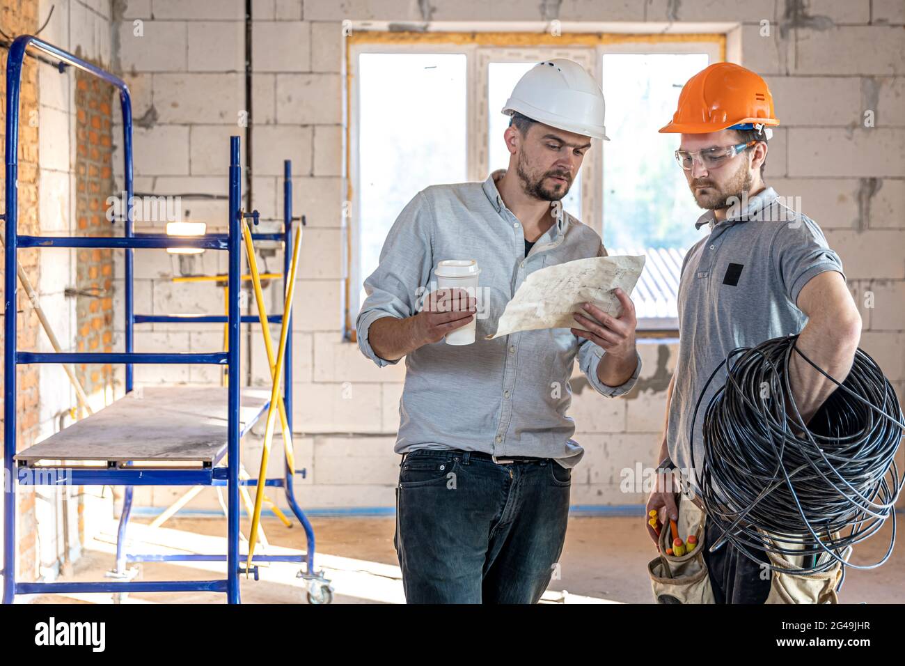 Two builder engineers talking at building site, engineer explaining a ...