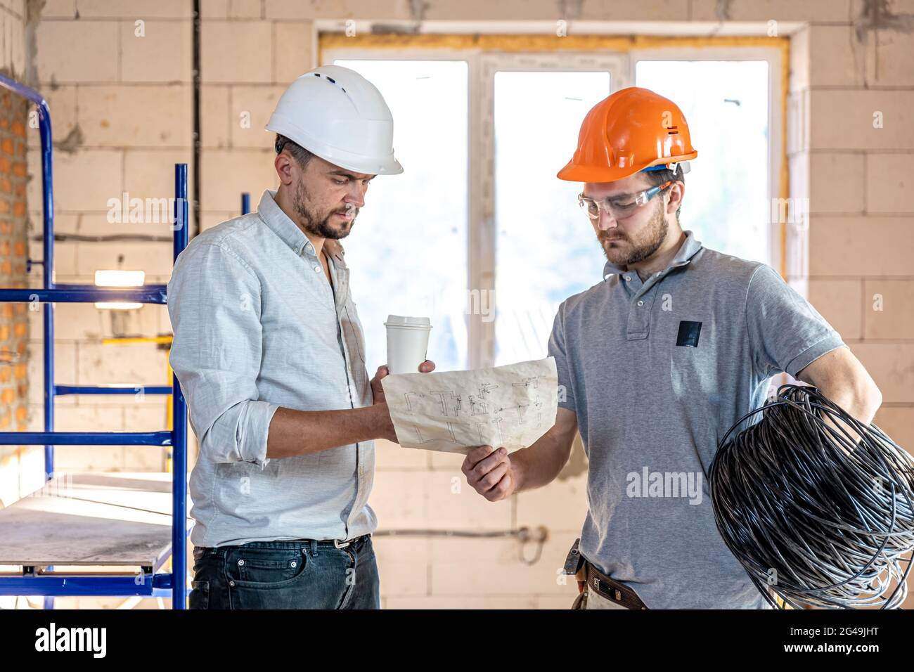 Two builder engineers talking at building site, engineer explaining a ...