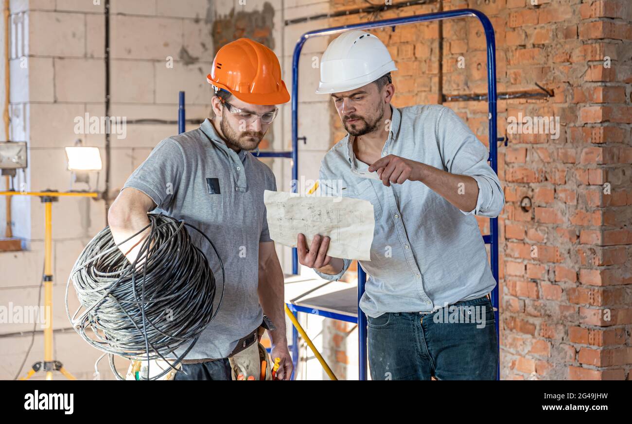 Two builder engineers talking at building site, engineer explaining a ...