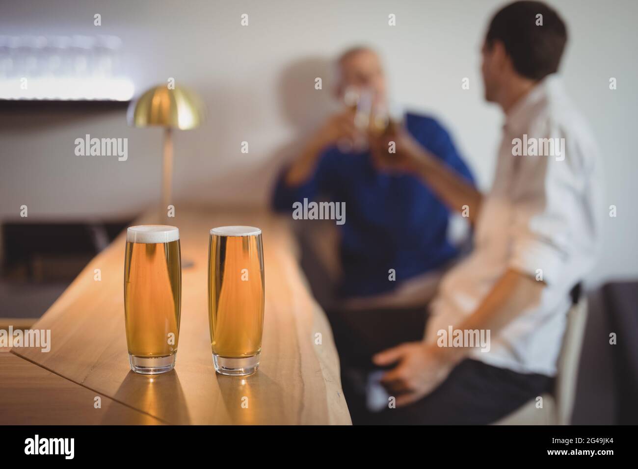 Glasses of beer at counter with customers in background Stock Photo - Alamy