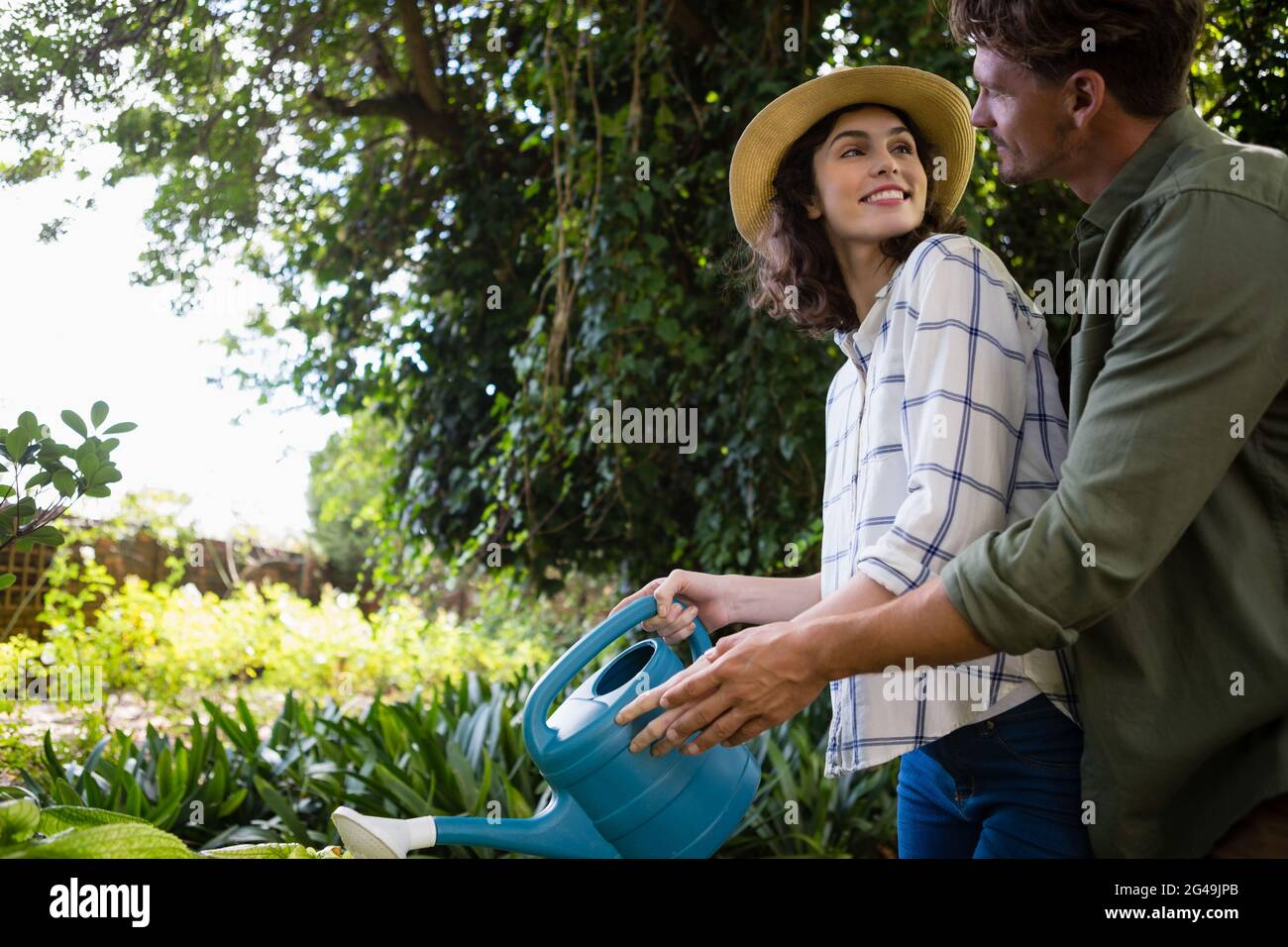 Romantic couple watering plants with watering can in garden Stock Photo ...