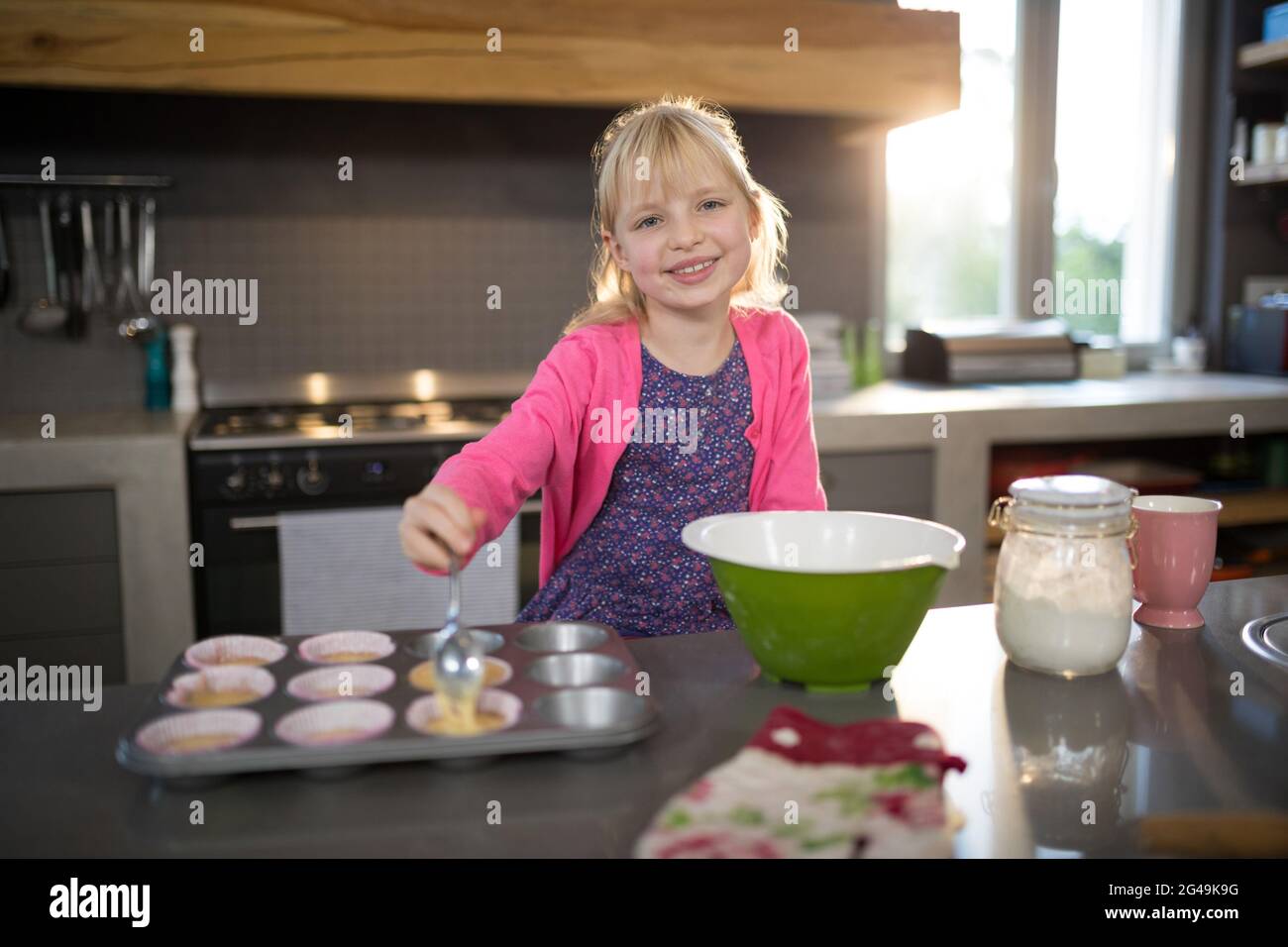 Smiling girl pouring cupcake batter Stock Photo - Alamy