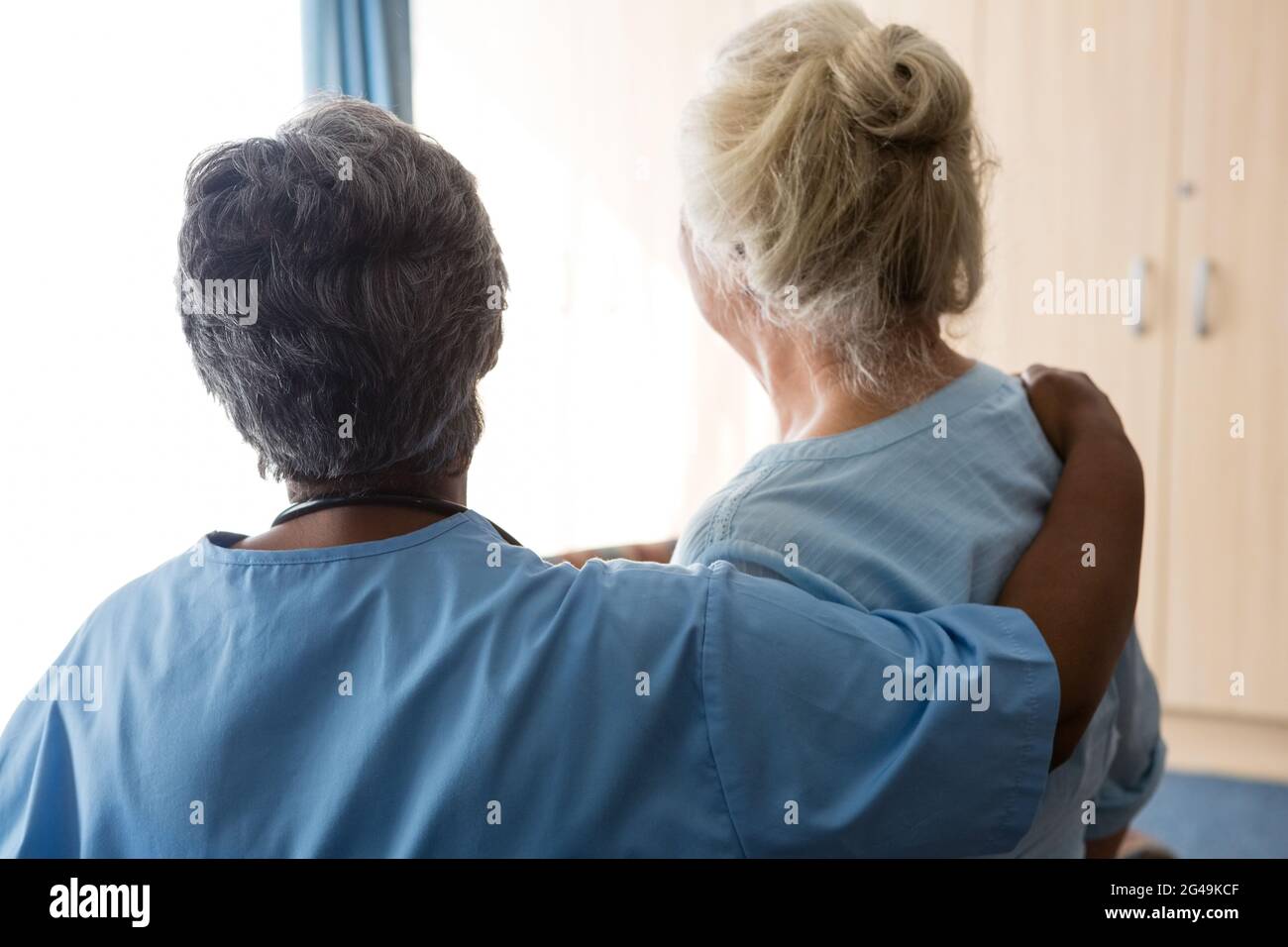 Rear view of nurse standing with senior woman Stock Photo - Alamy