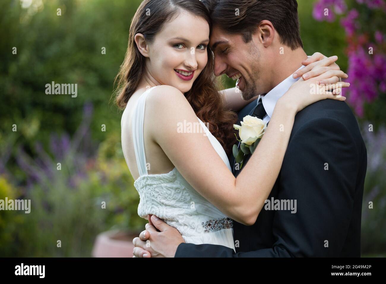 Happy bride embracing bridegroom while standing in park Stock Photo - Alamy