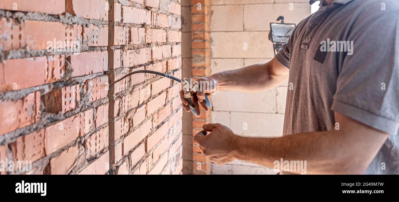 A construction electrician cuts a voltage cable during a repair Stock ...