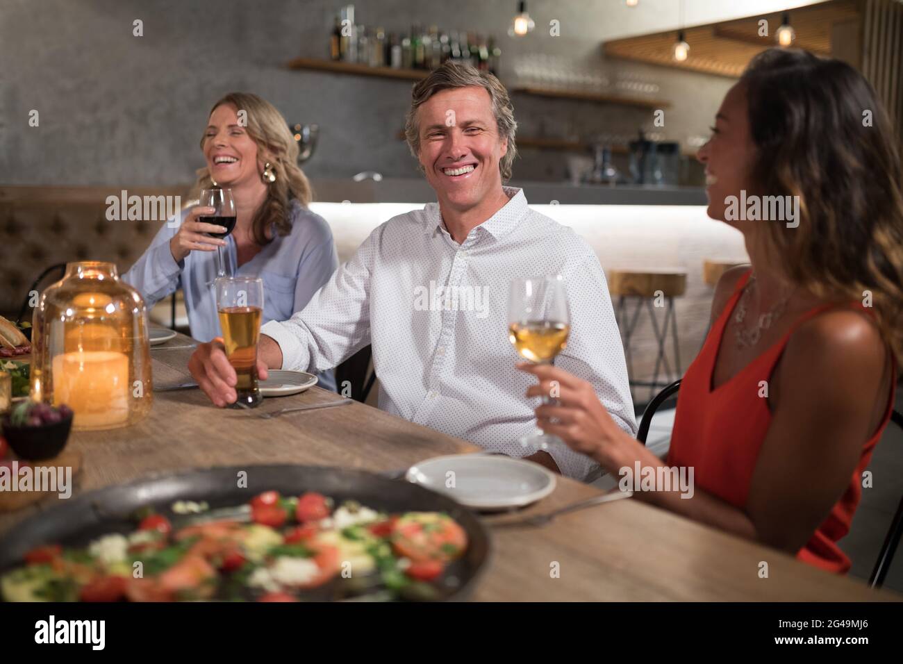 Friends interacting while dining in restaurant Stock Photo - Alamy