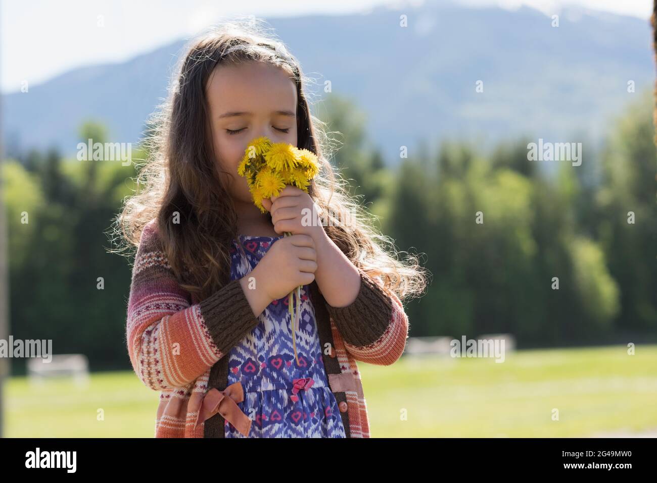 Cute girl smelling fresh flowers Stock Photo - Alamy