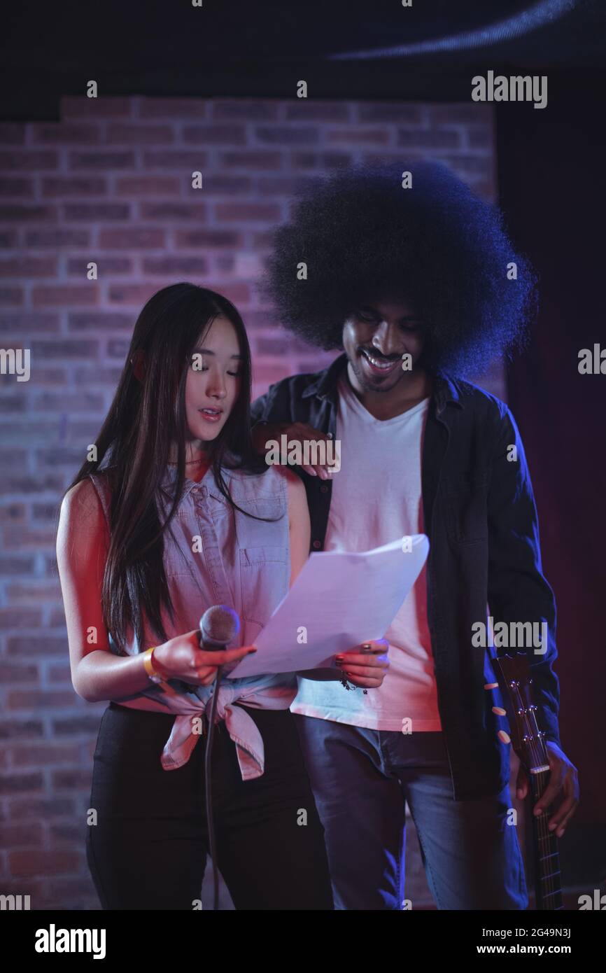 Singer with guitarist reading papers in illuminated nightclub Stock ...