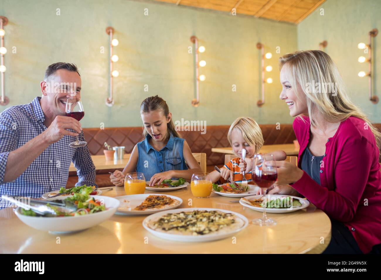 Happy family talking while having dinner Stock Photo - Alamy