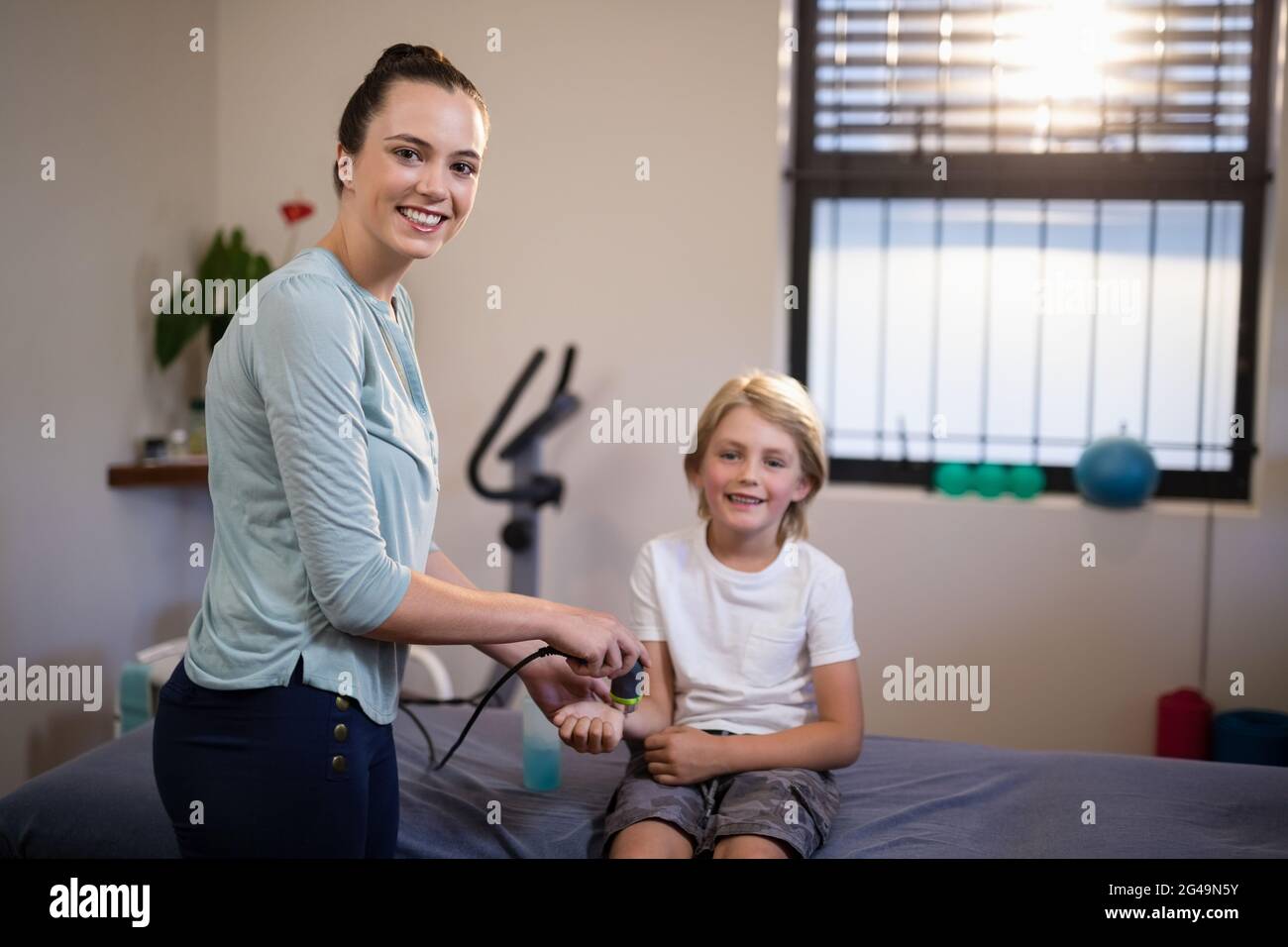 Portrait of smiling boy with female therapist scanning wrist Stock ...