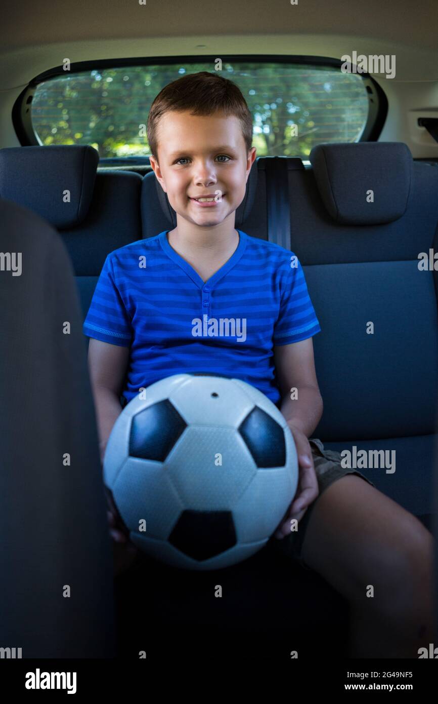 Happy teenage boy sitting with football in the back seat of car Stock ...