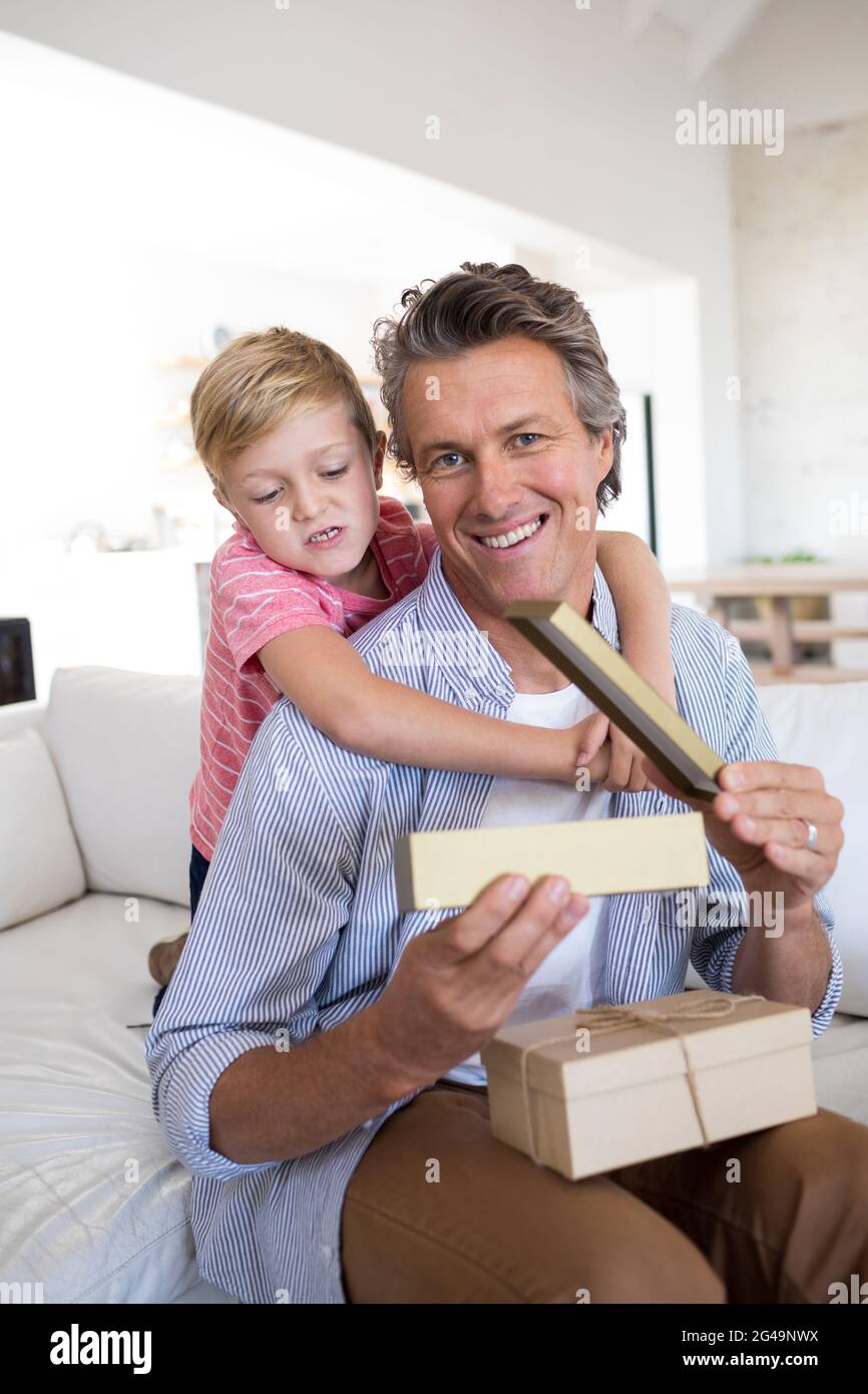 Son giving gift box to father in living room Stock Photo - Alamy