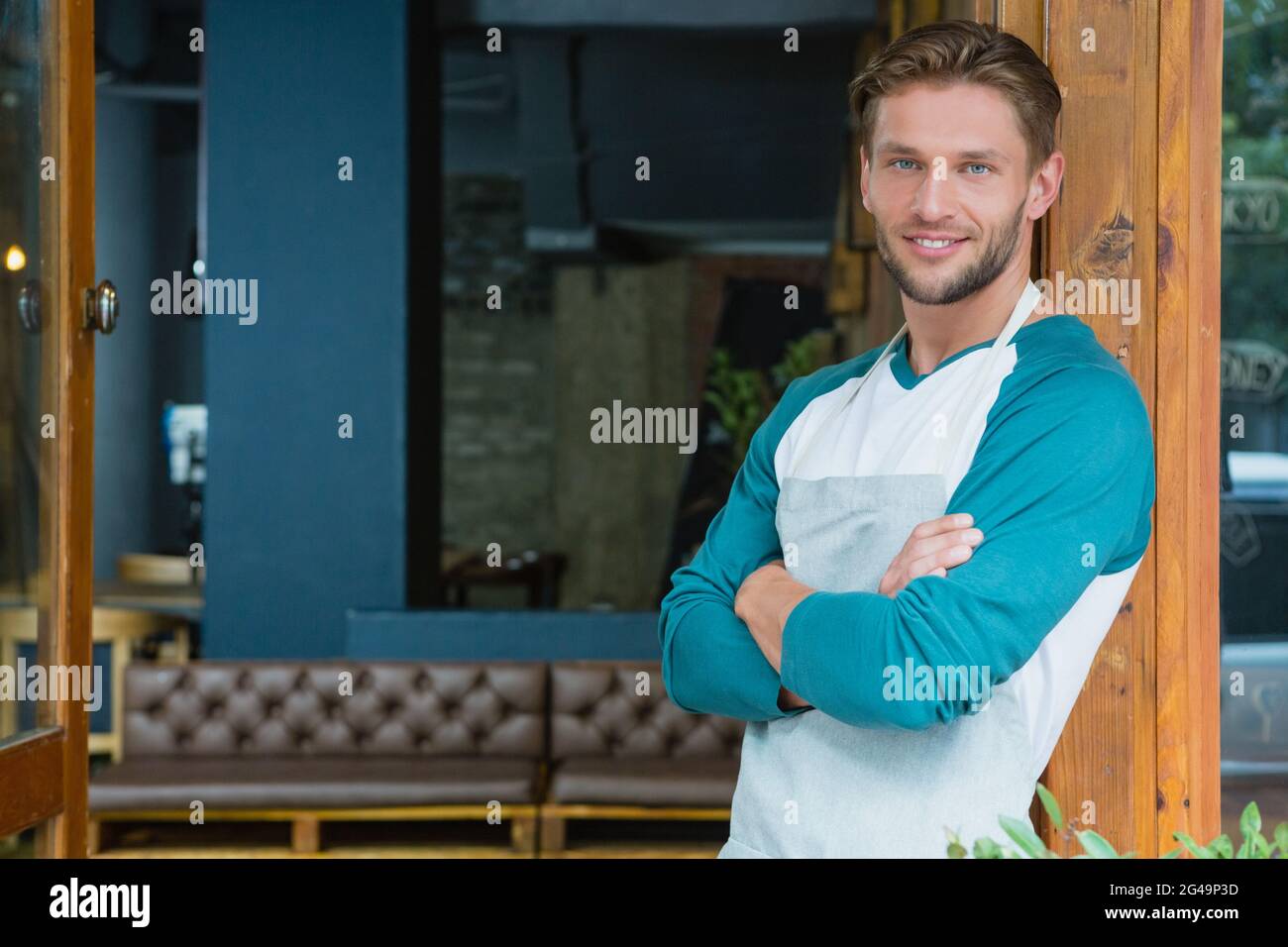 Portrait of smiling waiter standing with arms crossed Stock Photo - Alamy