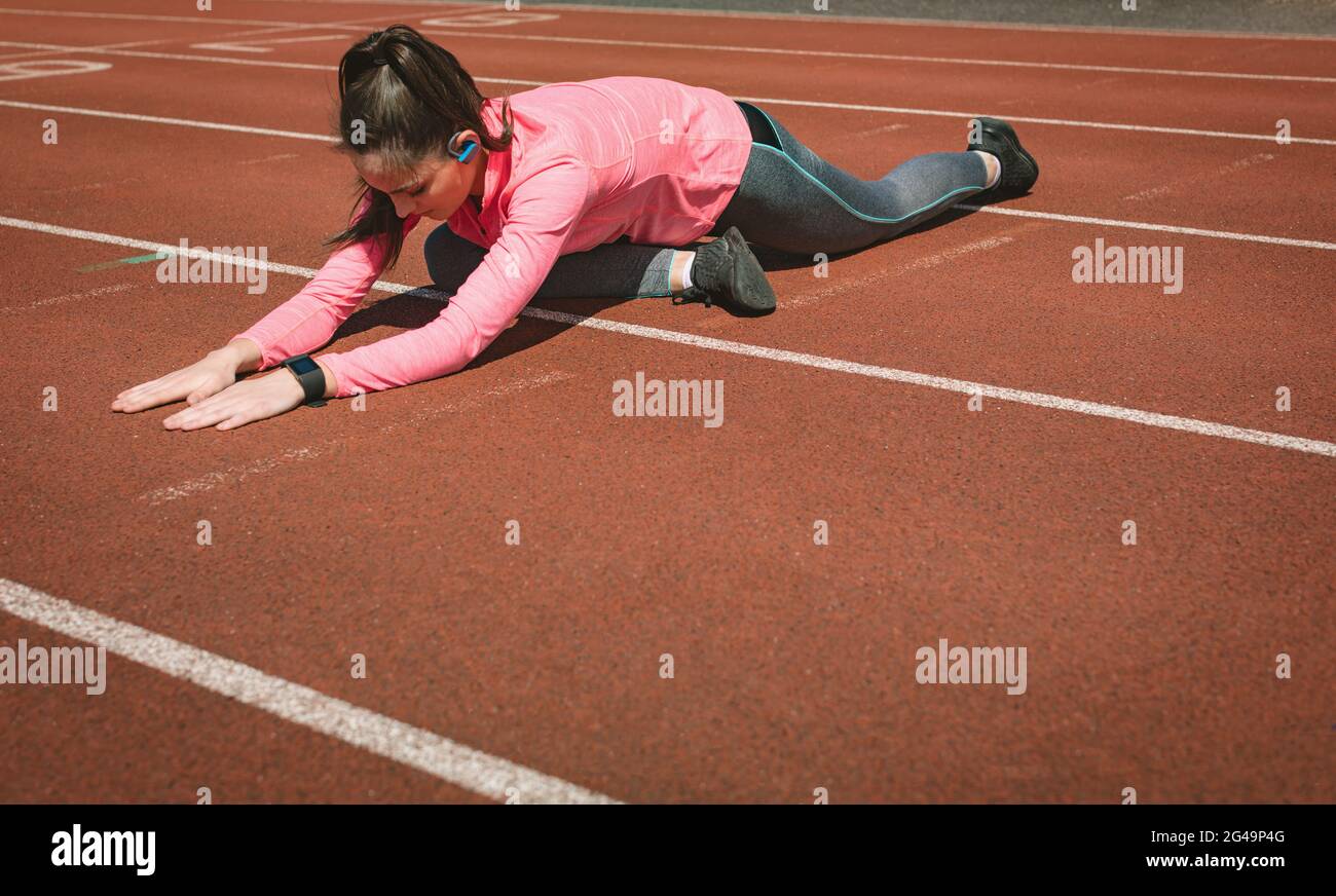 Woman performing stretching exercise on a race track Stock Photo - Alamy