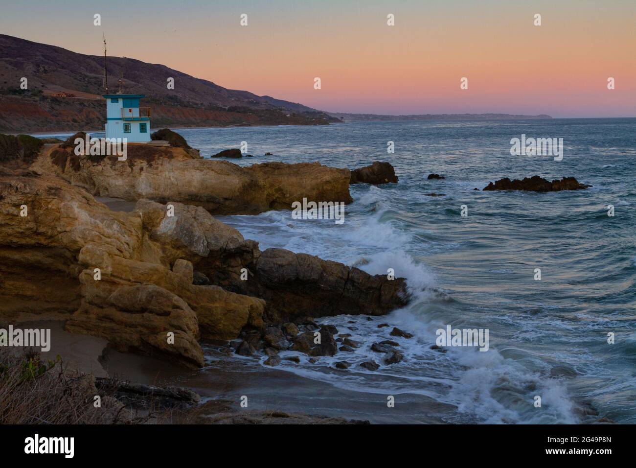 Lifeguard tower in Malibu at sunset with waves crashing along the coast ...