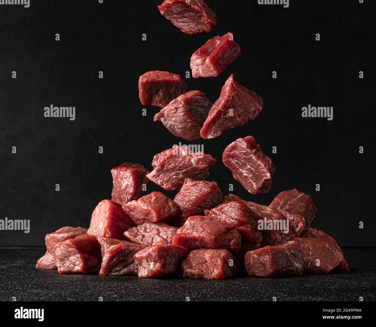 Cubes of raw beef falling over black background Stock Photo - Alamy
