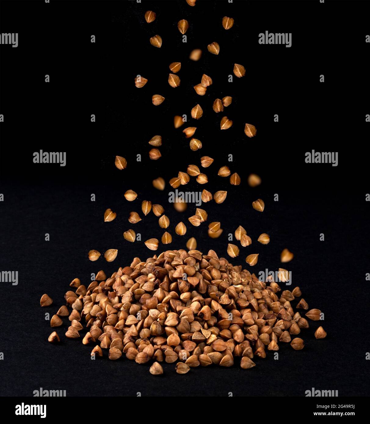 Falling buckwheat grains isolated on black background Stock Photo - Alamy