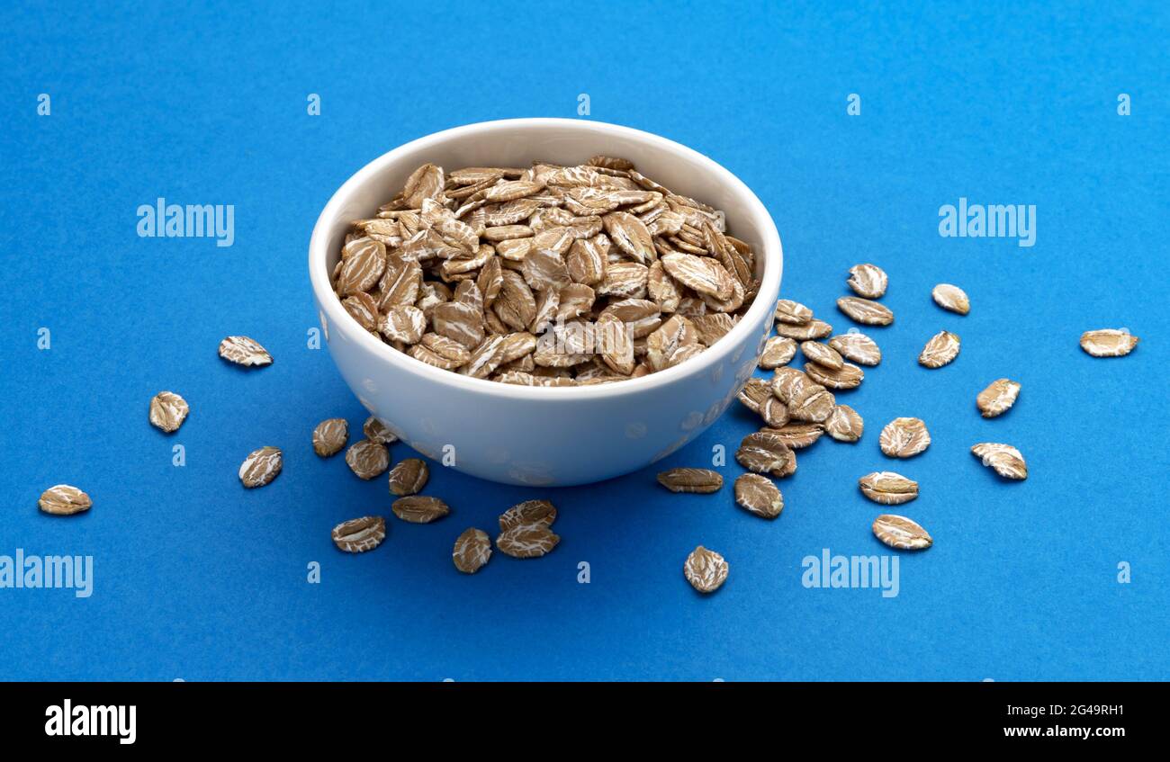 Oat rye flakes in bowl isolated on blue color background Stock Photo ...