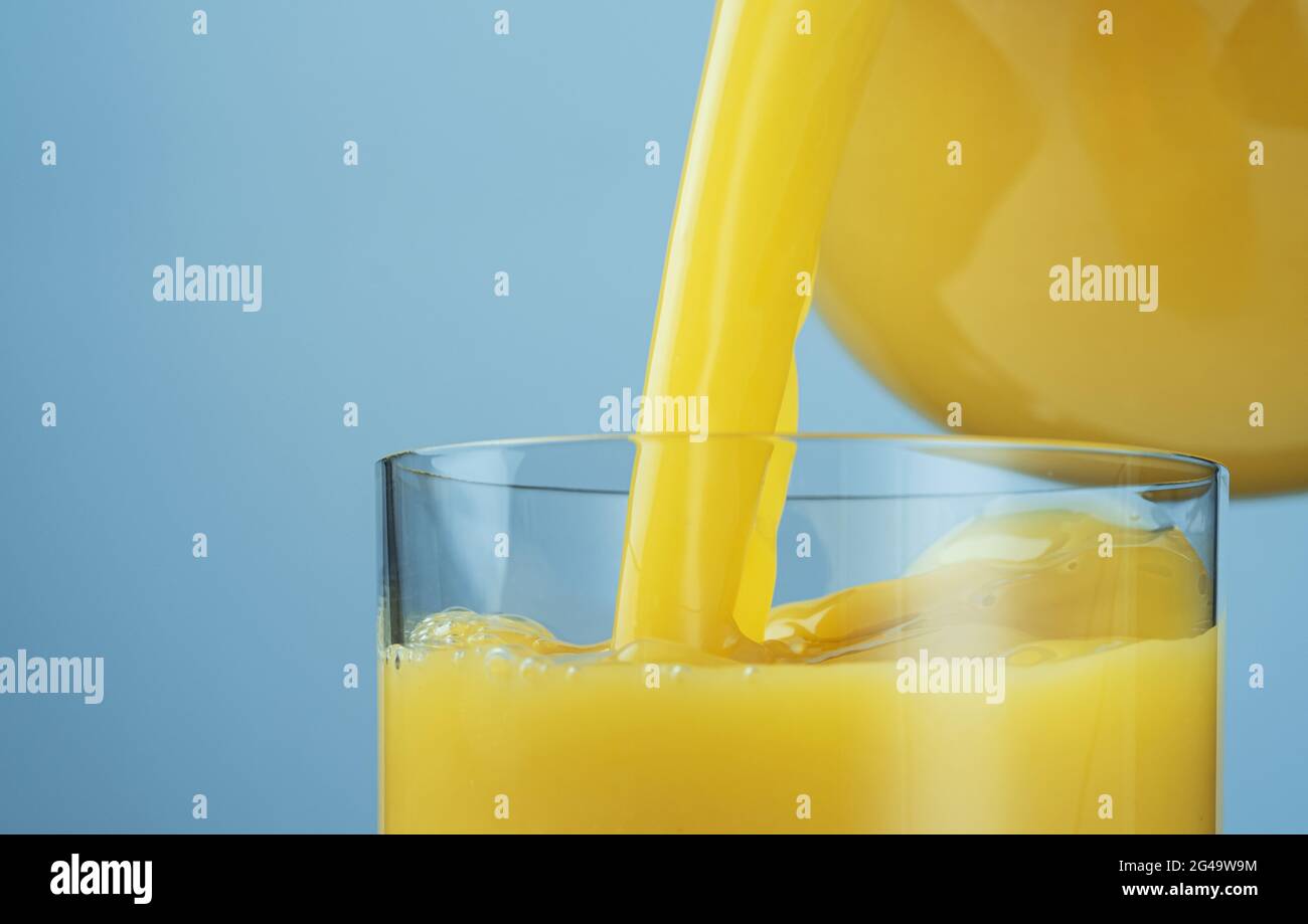 Orange juice pouring from jug into glass Stock Photo - Alamy