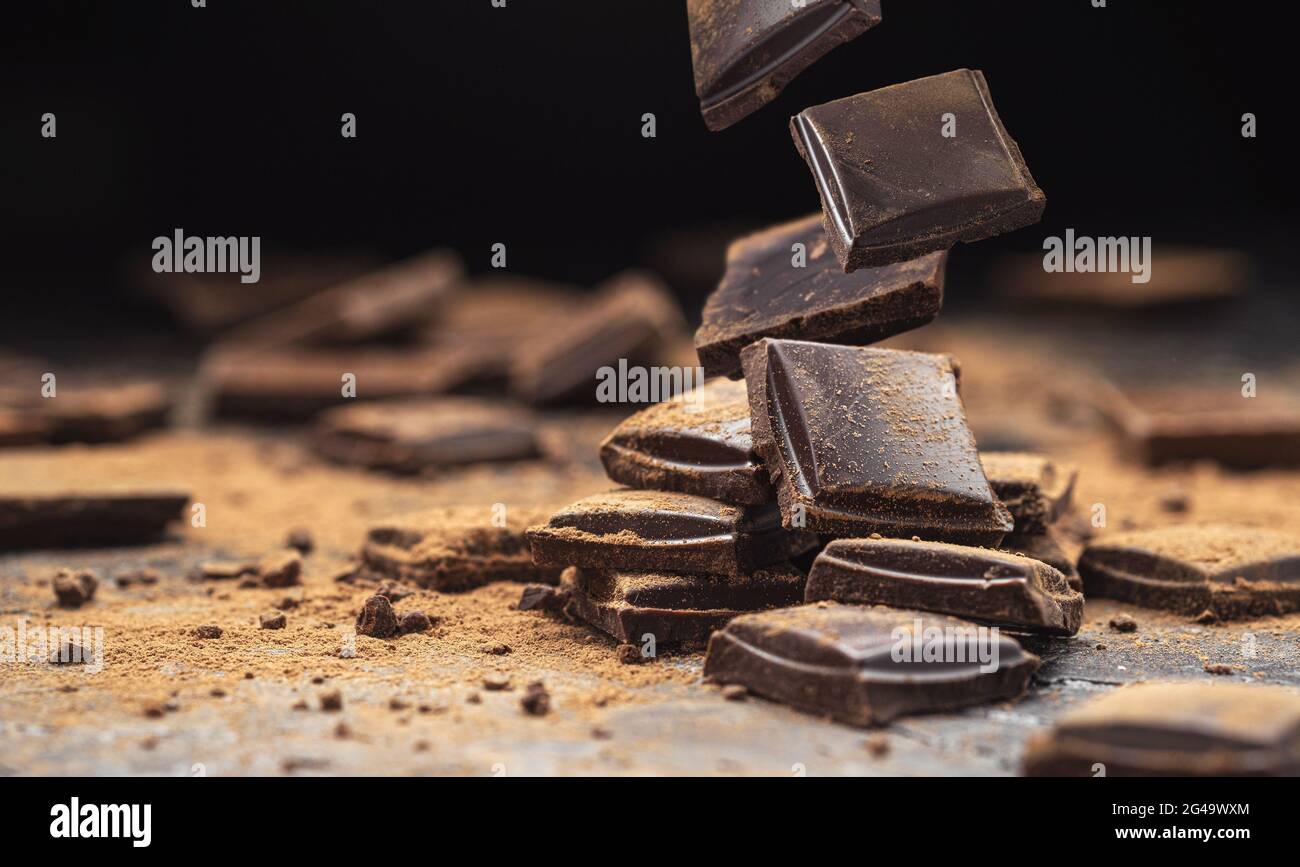 Falling broken chocolate bars on black background Stock Photo - Alamy