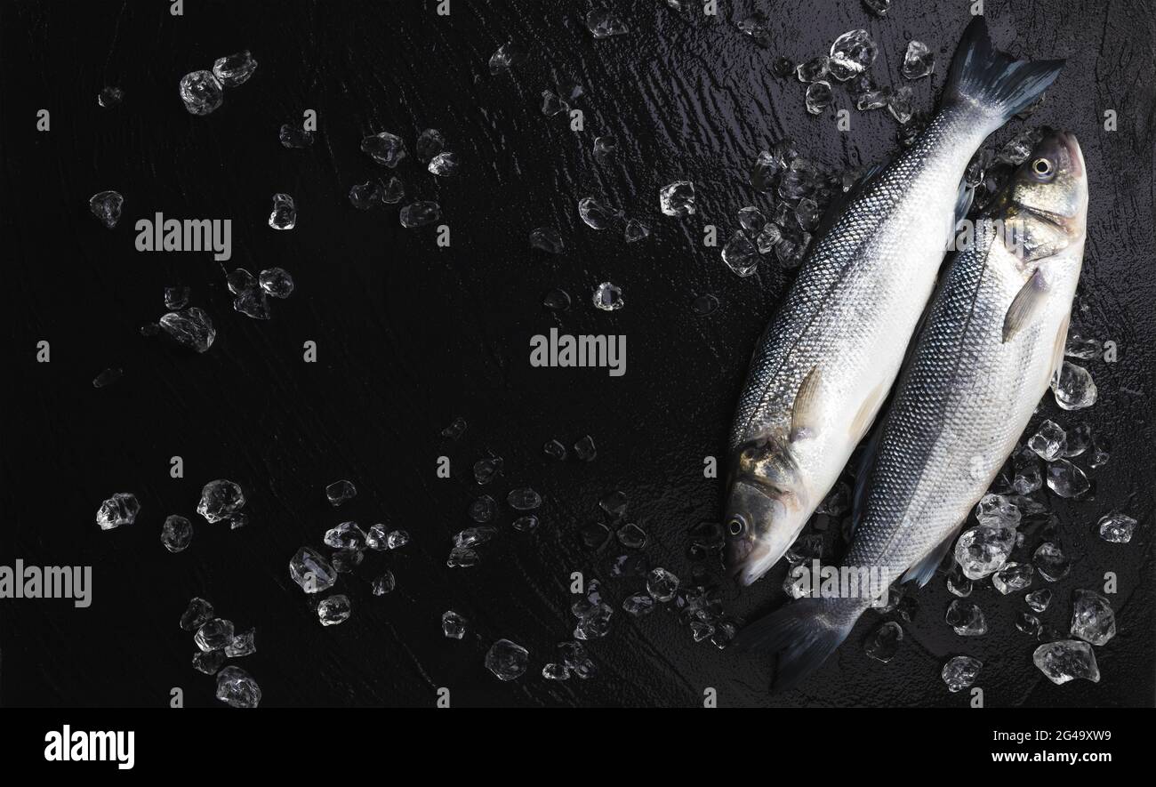 Seabass fish on ice on black stone background, top view Stock Photo - Alamy