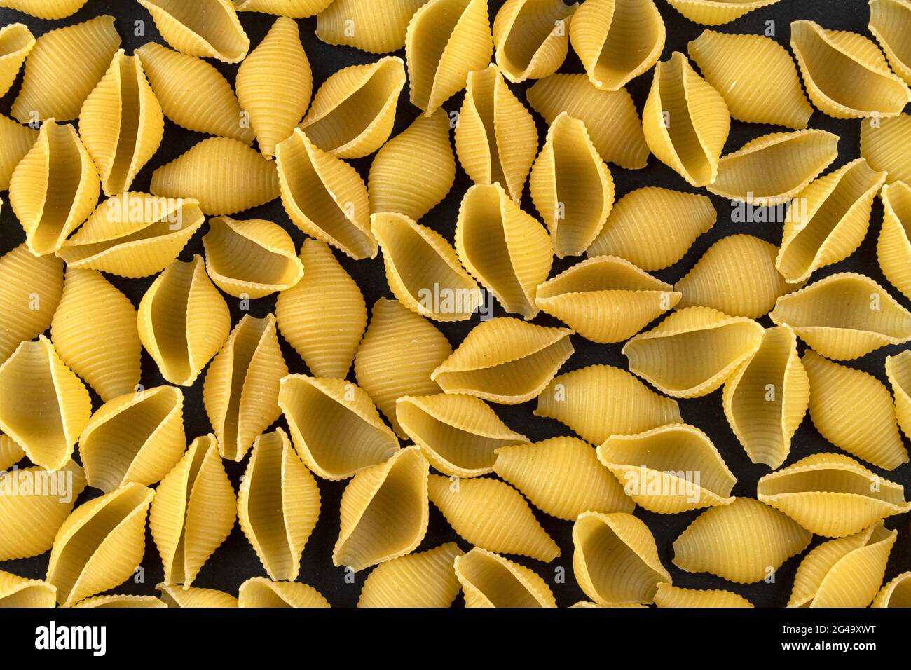 Dry shell pasta pattern on black background, top view Stock Photo - Alamy