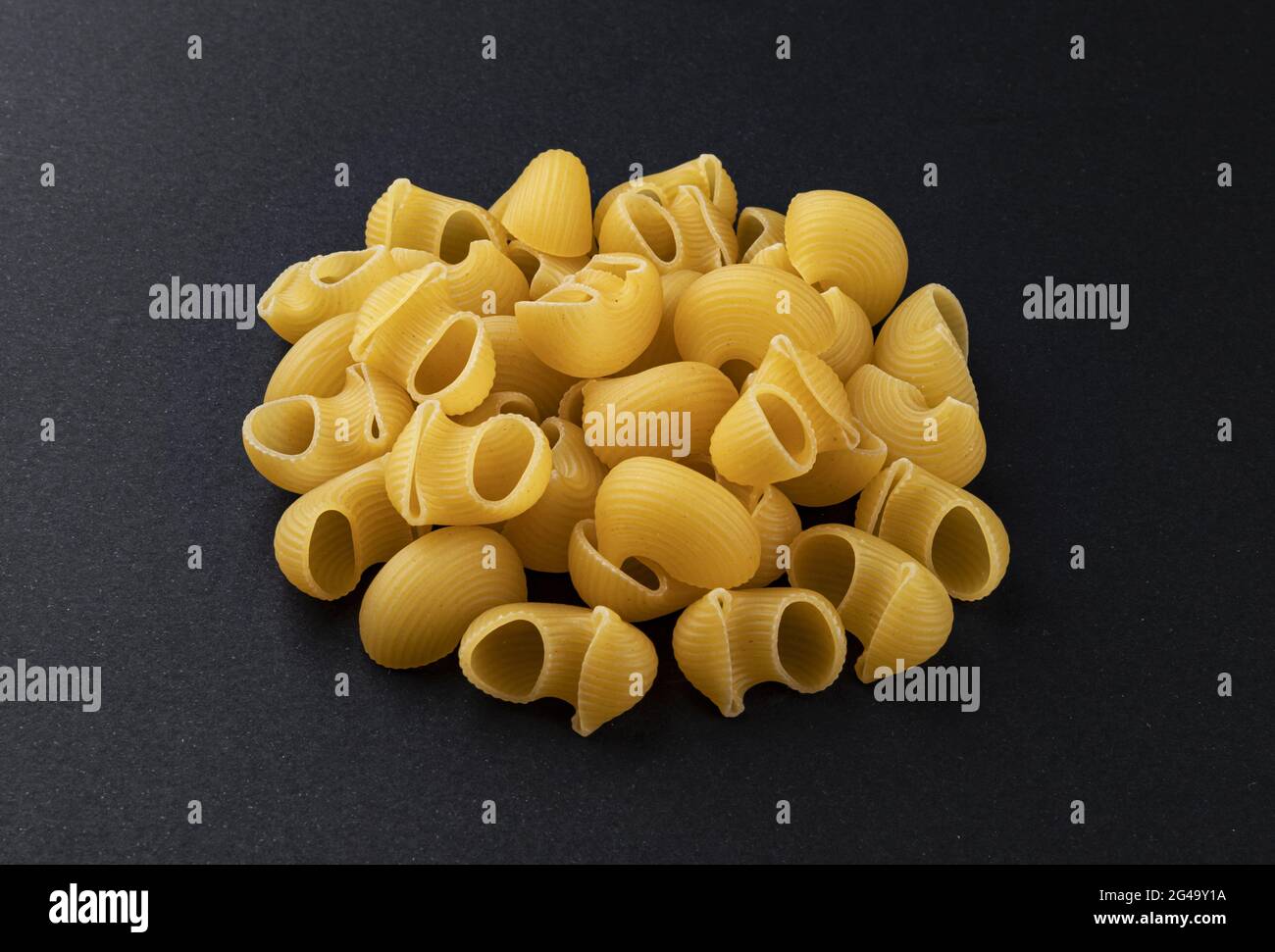 Raw pipe rigate pasta isolated on black background Stock Photo - Alamy