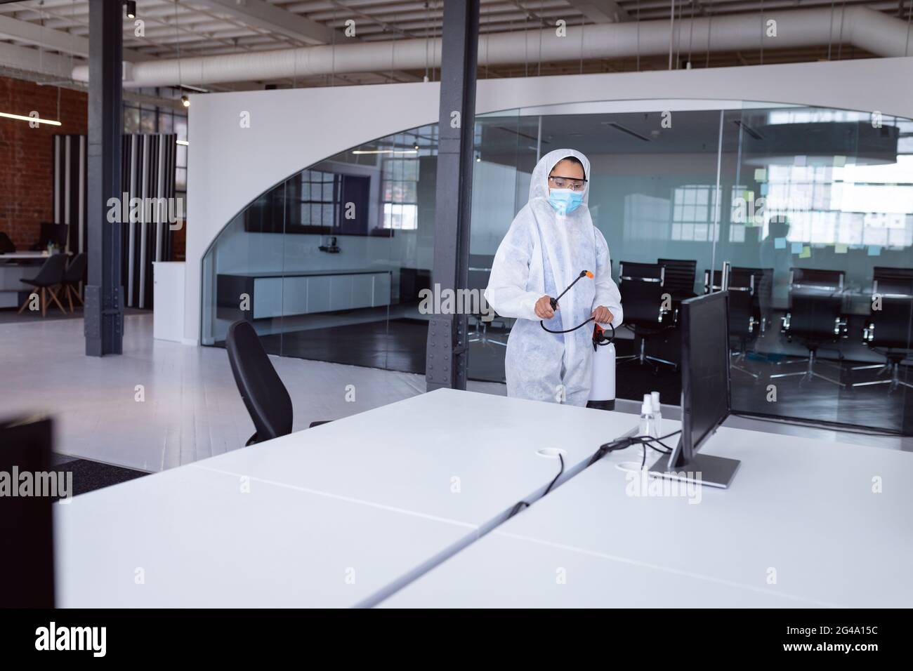 Cleaner wearing ppe suit, glasses and mask disinfecting office ...