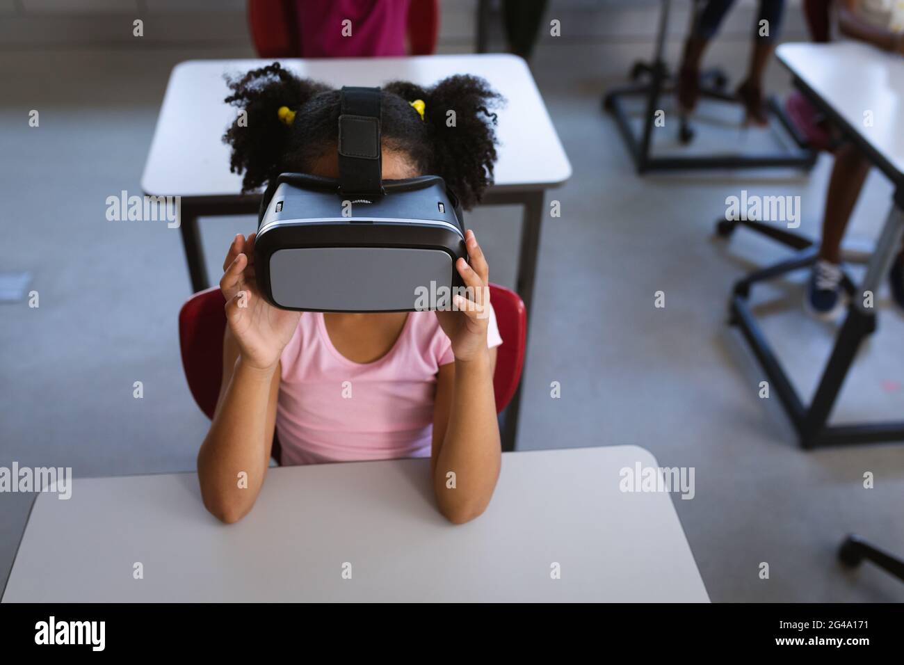African american girl wearing vr headset while sitting on her desk in ...