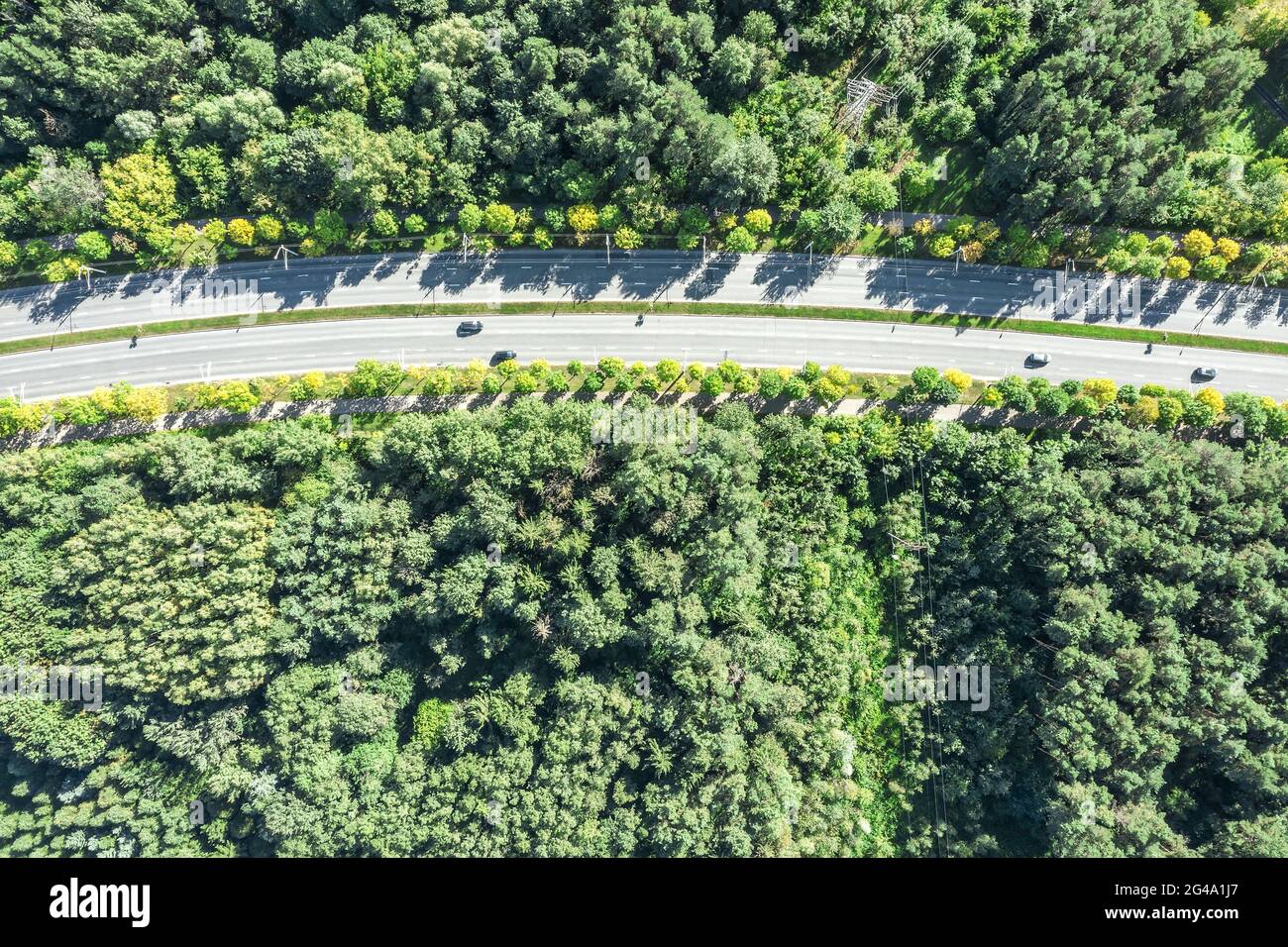 aerial view of road with car traffic going through green summer forest ...
