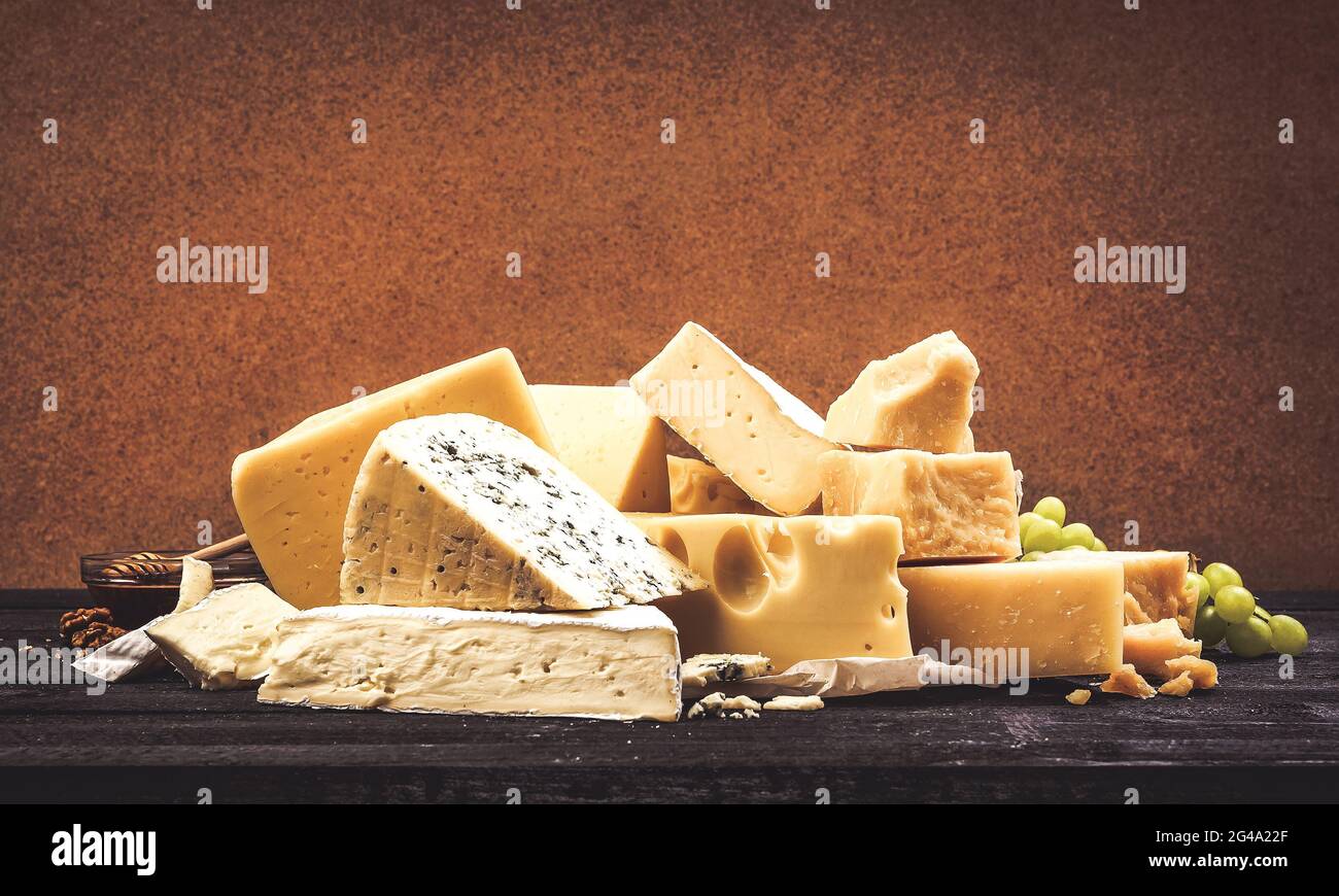 Different types of cheese on black wooden table background Stock Photo ...