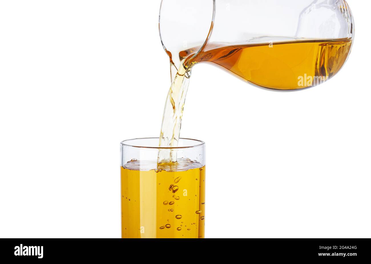 Apple juice pouring from pitcher into glass isolated on white ...