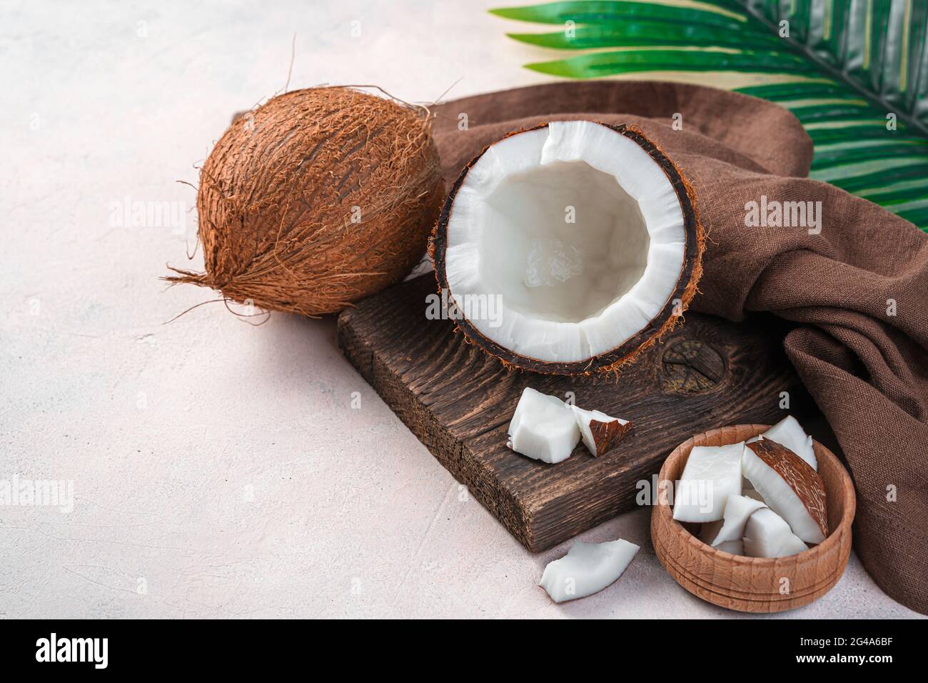Ripe coconut on a light pink background with a palm branch. Tropical ...