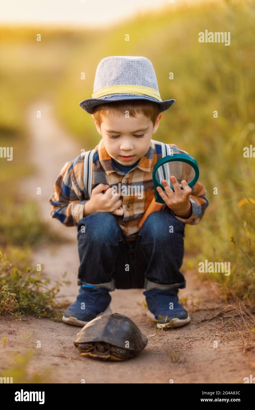 little boy exploring nature in the meadow with a magnifying glass Stock ...